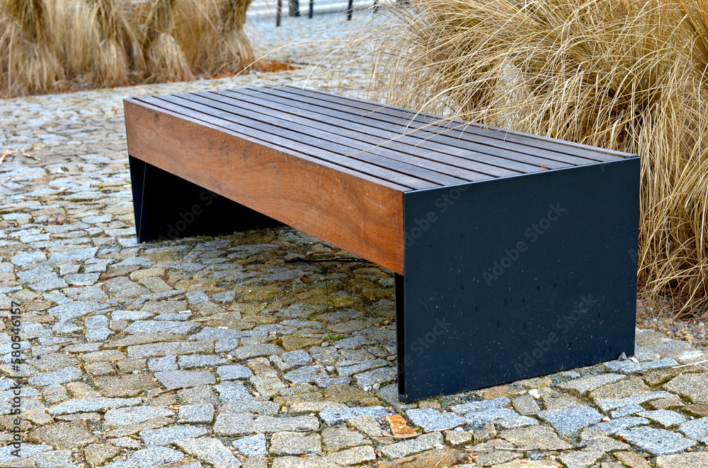 wooden modern park bench with a metal relief structure on one leg ...