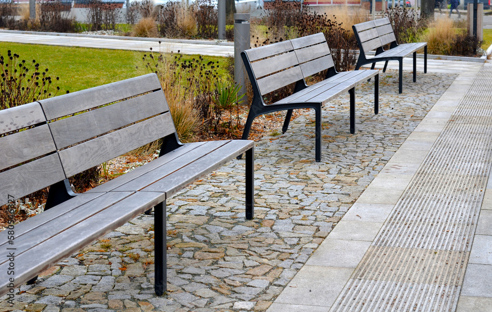 wooden modern park bench with a metal relief structure on one leg ...
