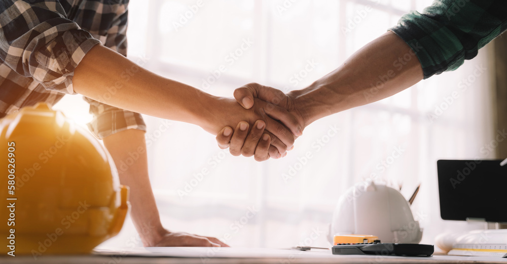 Construction workers, architects and engineers shake hands while ...