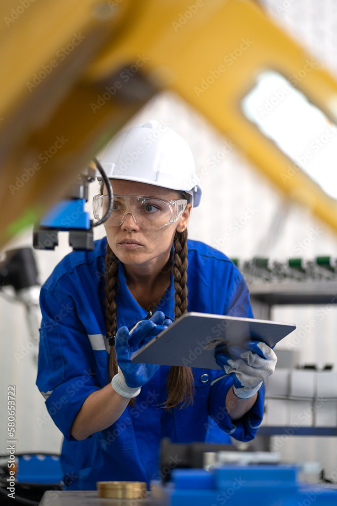 Robotic maintenance engineer working on robot arm connection using tablet computer. Smart women ...