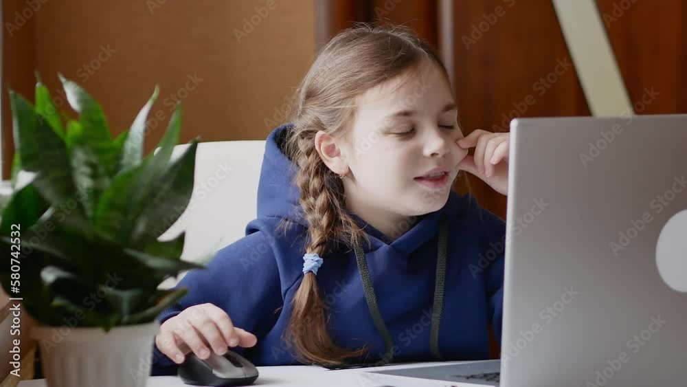 A little girl with pigtails sits at a table with a laptop, pronounces ...
