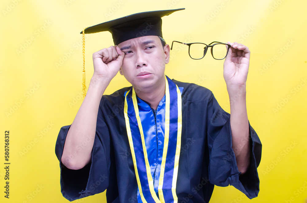 sad Asian man in graduation cap and gown rubbing his tears. student ...