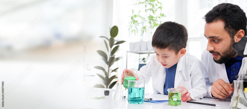 Lovely Asian young boy in lab coat enjoy doing an experiment and ...