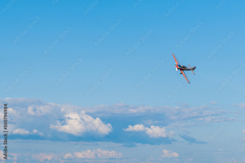 Small retro airplane, light aircraft flying in blue cloudy sky and ...