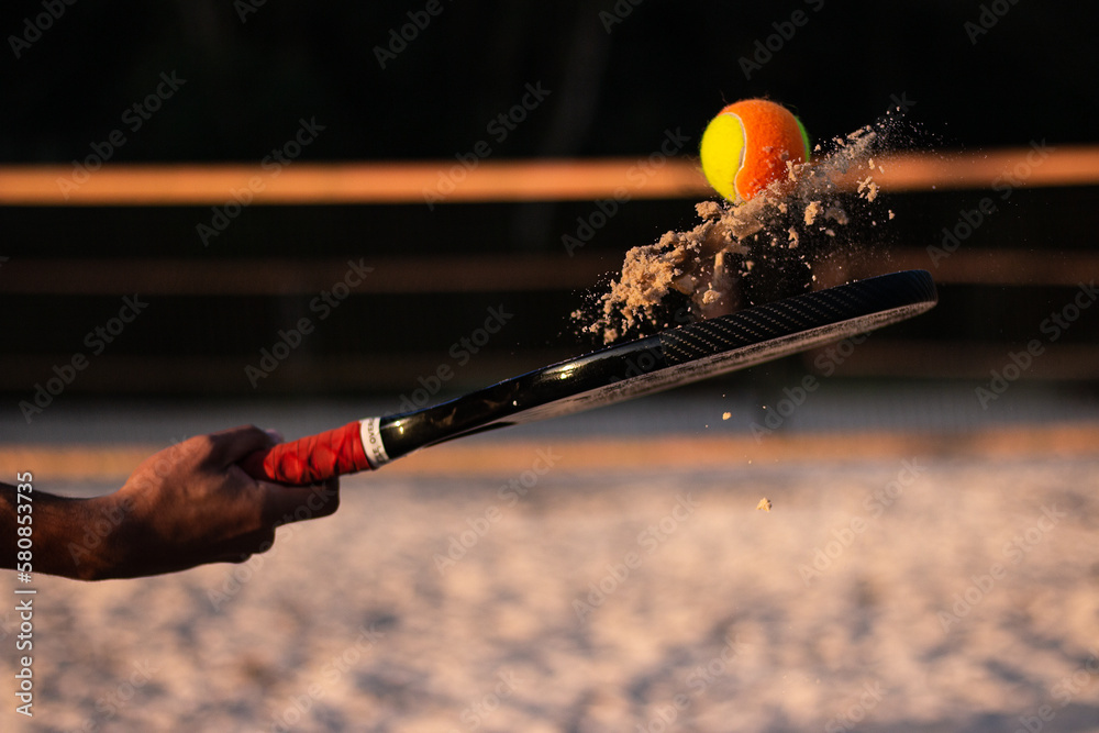 Foto de Beach tennis racket and ball. Man holding racket with sand and ...