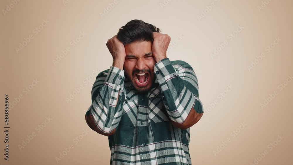 Young indian man scared fearful, covering ears with hands, closing eyes ...