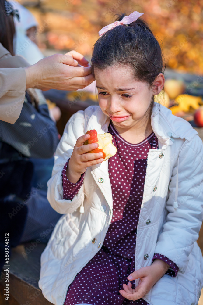 The girl is crying and eating an apple, she is sad, she is upset. Mom ...