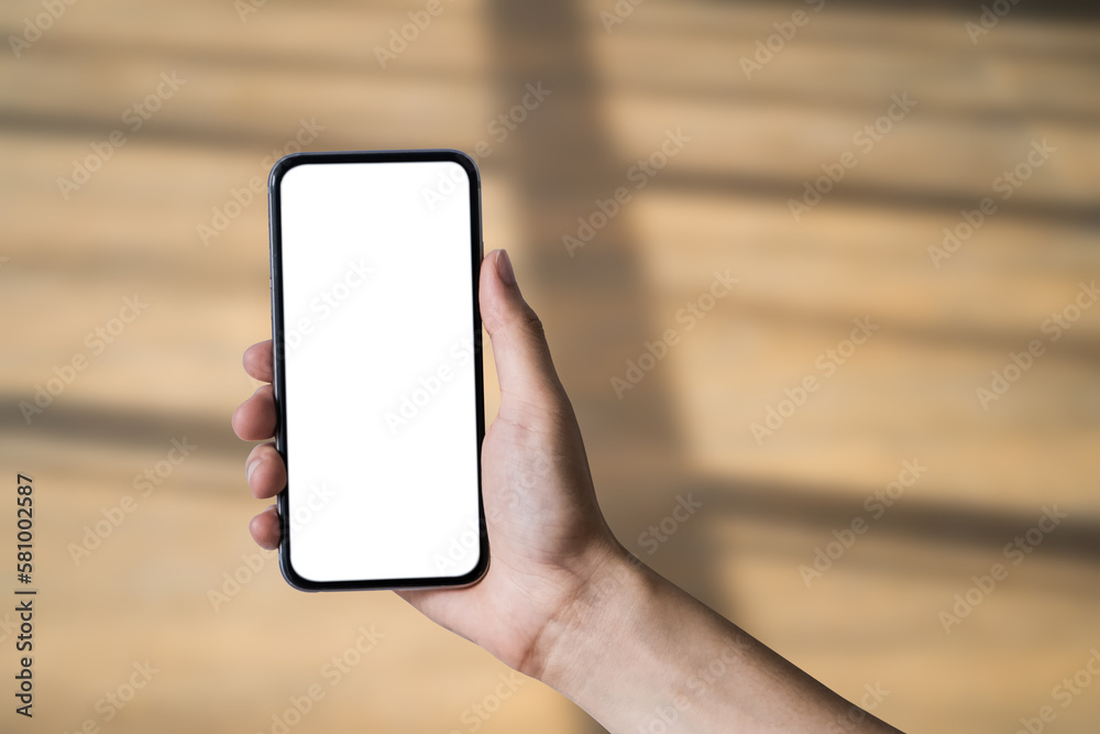 Hand holding white mobile phone with blank white screen in blur shadow ...