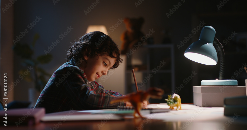 Funny little asian kid drawing at home. Boy with curly hair using his ...
