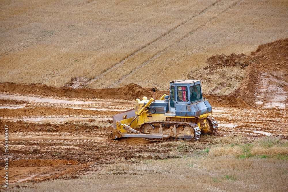 Bulldozer leveling ground on the field, construction site. Road ...