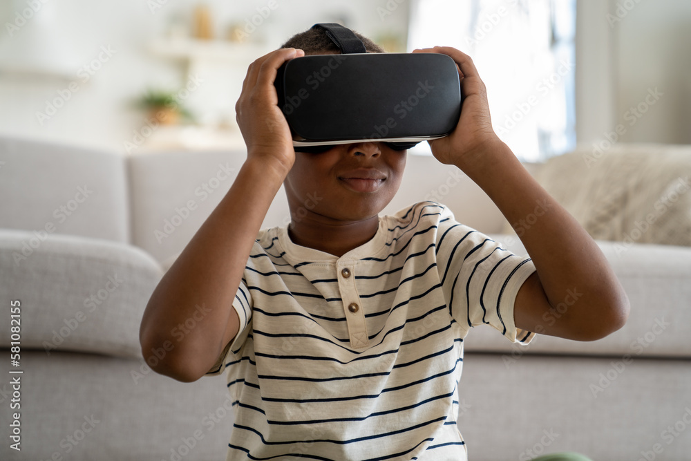 Curious African American kid boy wearing virtual reality 3D glasses ...