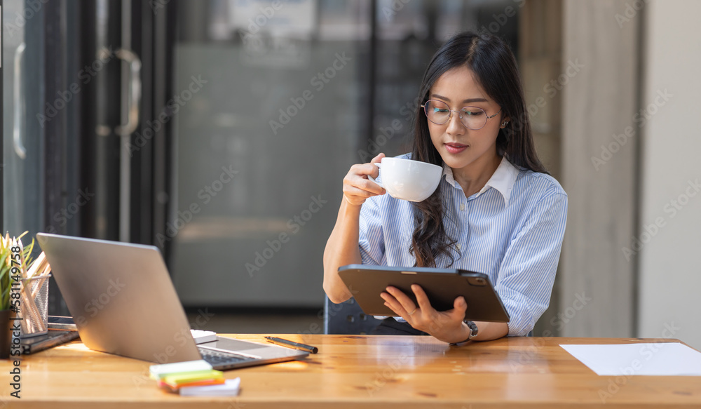 Beautiful young Asian woman working on laptop computer while sitting at ...