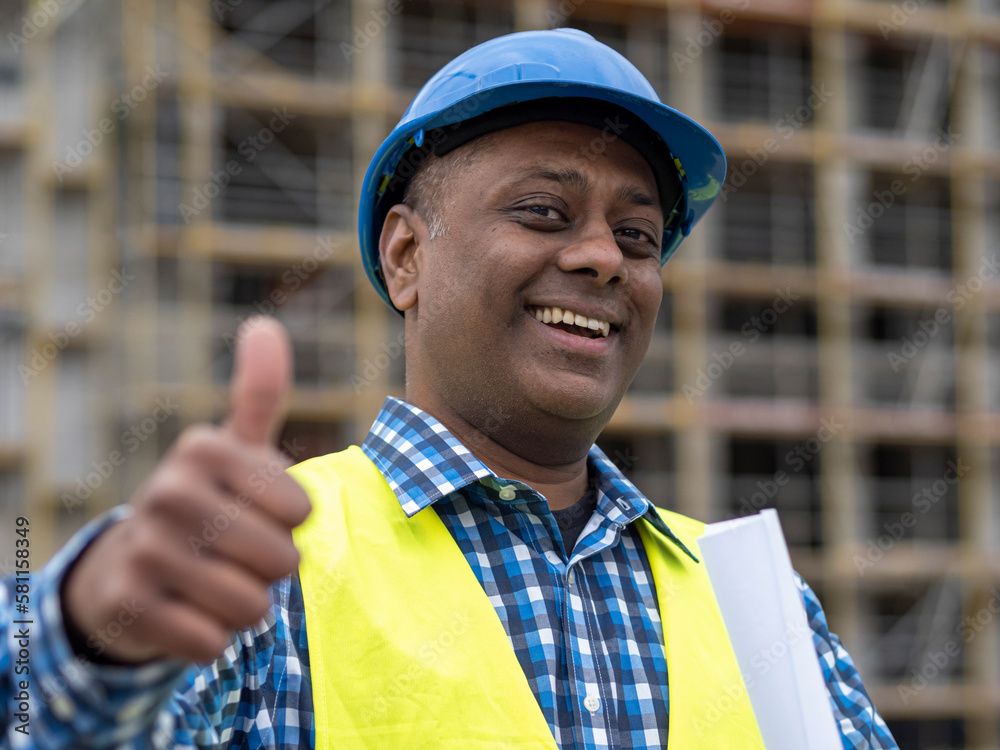 Smiling Indian construction worker wearing safety helmet and vest ...