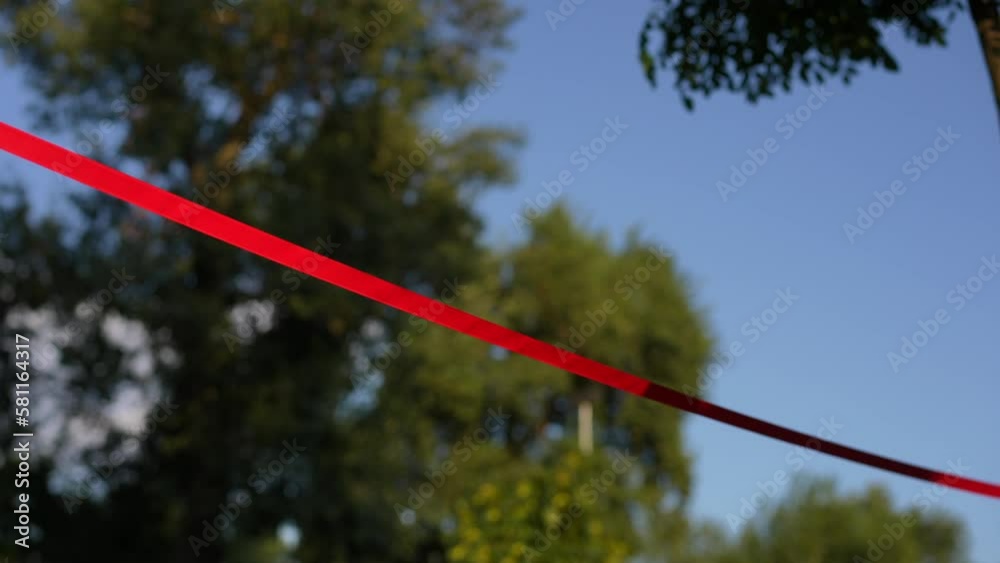 Close-up red ribbon at background of blue sky and green trees with fit ...