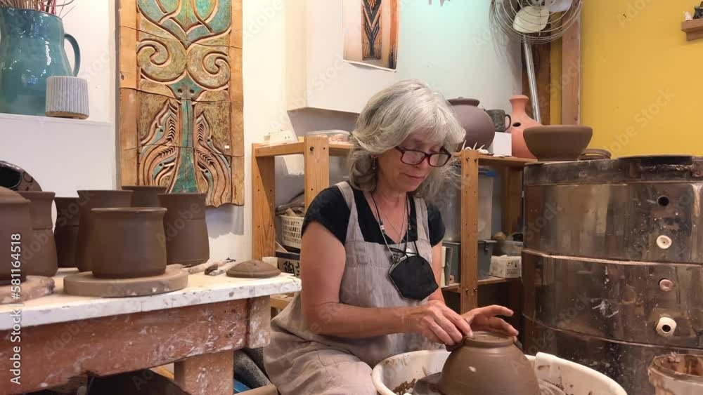 A woman makes makitra on a potter's wheel she levels it cutting off the ...