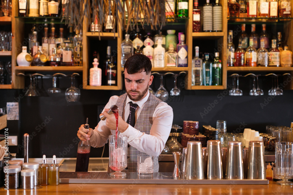 Young mixologist making a special cocktail for his clients in a bar ...