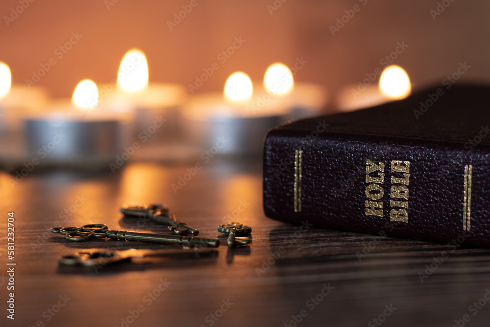 Holy bible book and ancient keys with burning candles on a dark ...