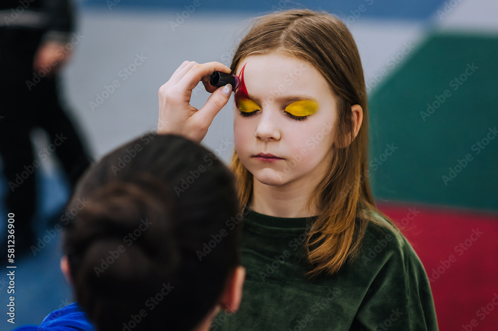 A professional make-up artist, artist paints with a brush on her face ...