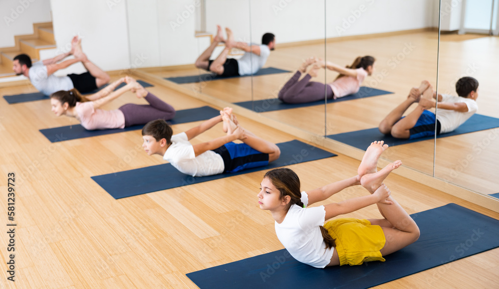 Concentrated teen girl doing back bending asana Dhanurasana known as ...