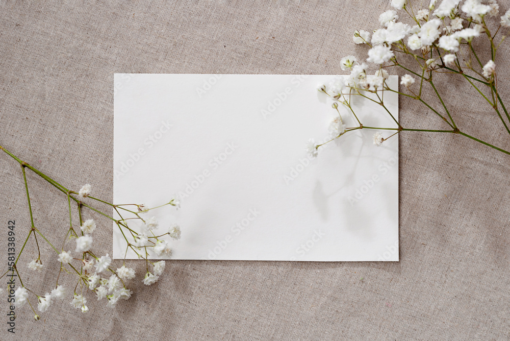 Blank paper card and gypsophila flowers on neutral beige linen texture ...