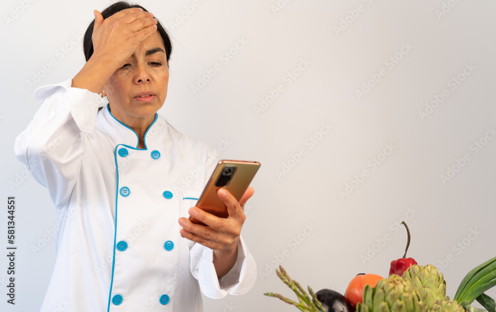 Worried latin woman chef looking at a message on her mobile trying to ...