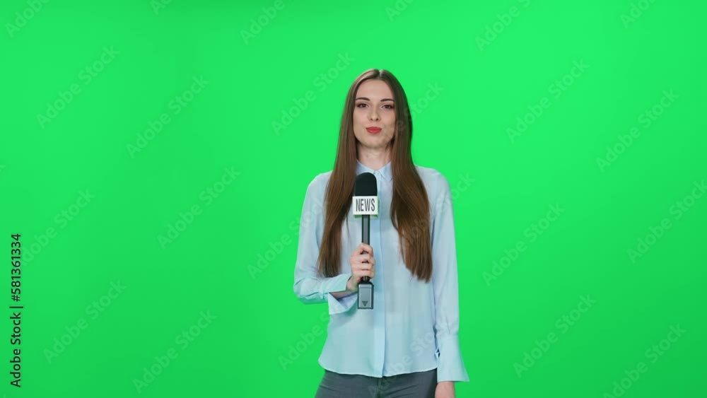Woman reporter looks into the camera and speaks, green background ...