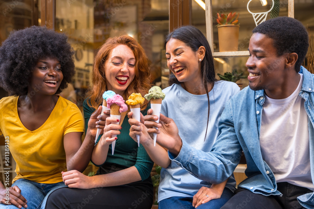 Multi-ethnic friends in an ice cream parlor sitting eating an ice cream ...