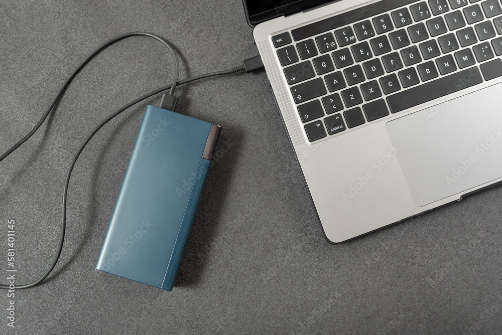 Power Bank is charged laptop. Laptop is connected by cord to an ...