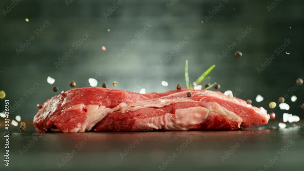 Flying piece of raw beef steak falling on table. Spice falling with ...