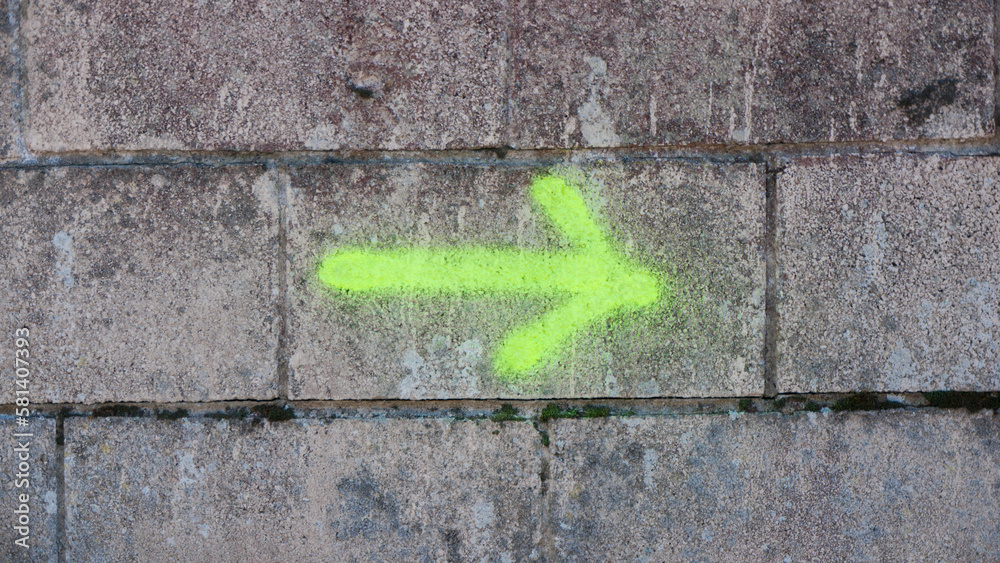 Flecha pintada con spray amarillo fluor en pared de bloques de hormigón ...