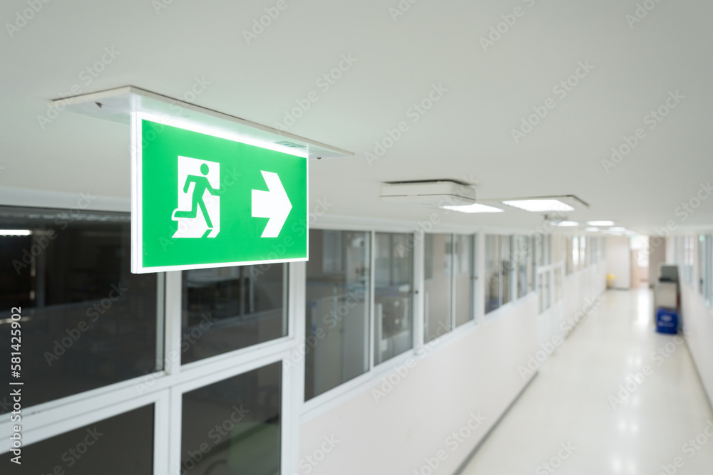 Selective fire exit sign on white ceiling.Green fire escape sign hang ...