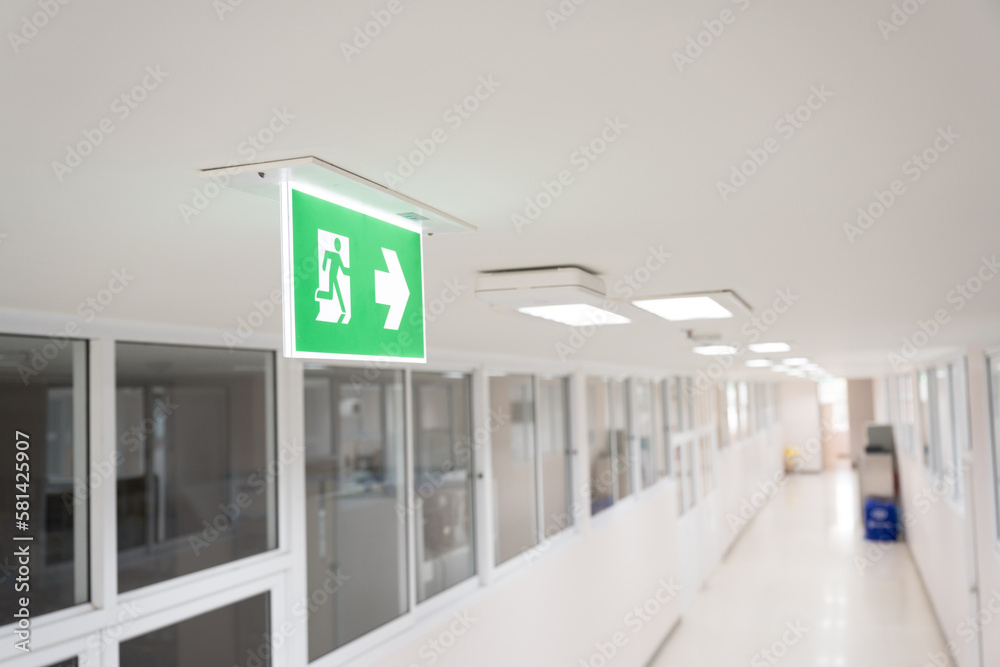 Selective fire exit sign on white ceiling.Green fire escape sign hang ...