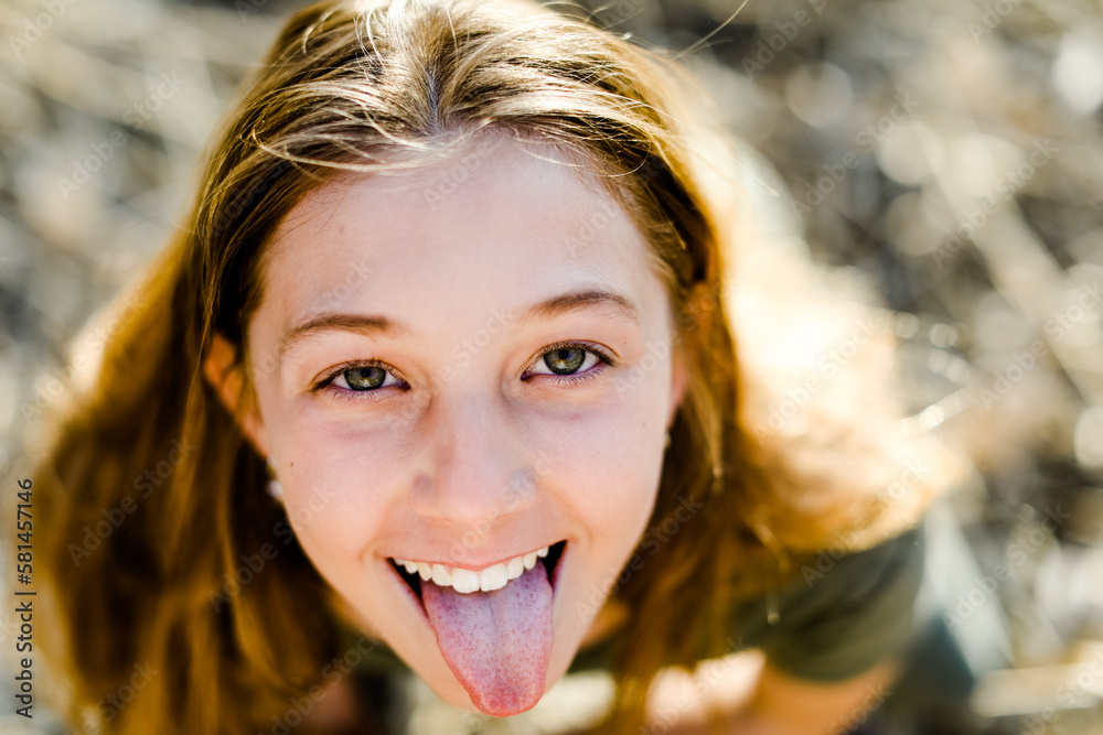 Foto de freches Mädchen lacht in die Kamera und zeigt die Zunge do ...