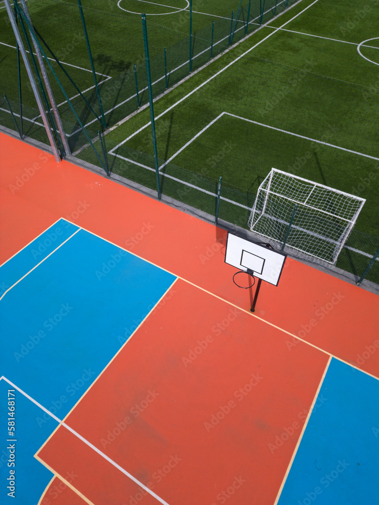 aerial view of a green football field and a colorful basketball court ...