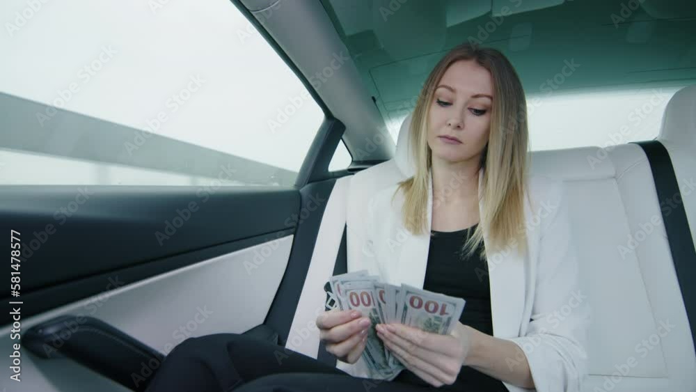 Caucasian woman counts dollar bills in the back of a car. Slow-motion ...