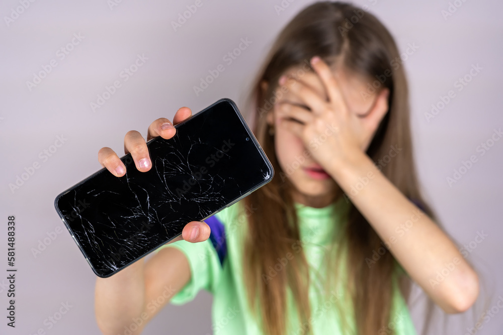 Scared little girl with emotional expression showing broken smartphone ...