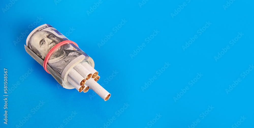 Cigarettes wrapped in 100 dollar bills on a blue background. The ...