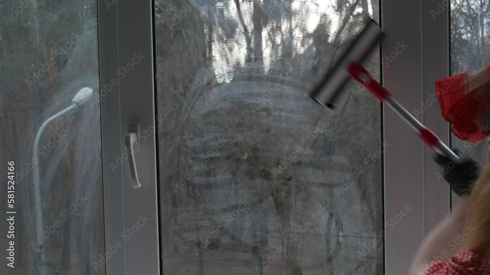 The girl cleans the window with a mop. Hand washes window glass with ...
