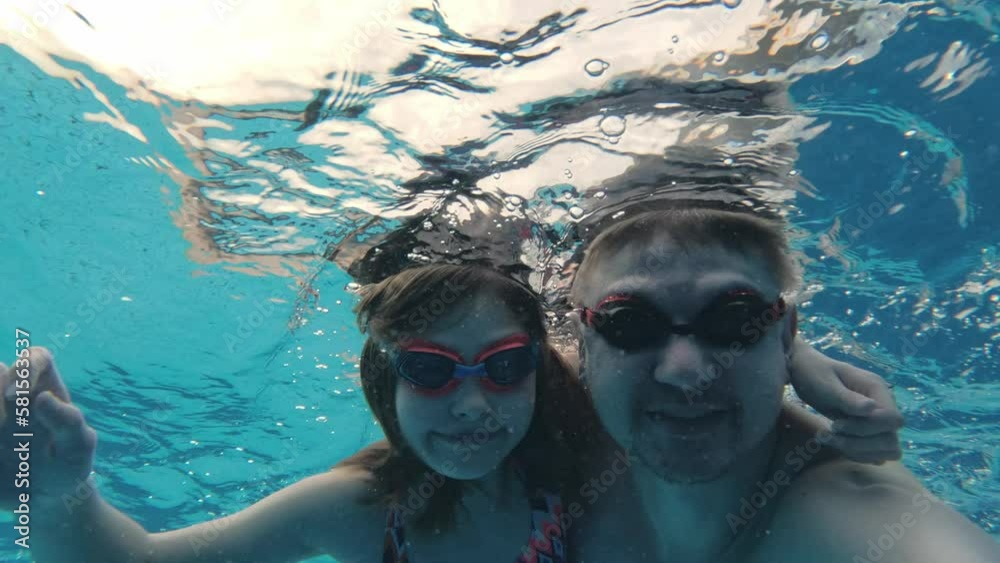 Young father man with preteen daughter child swimming in pool under ...