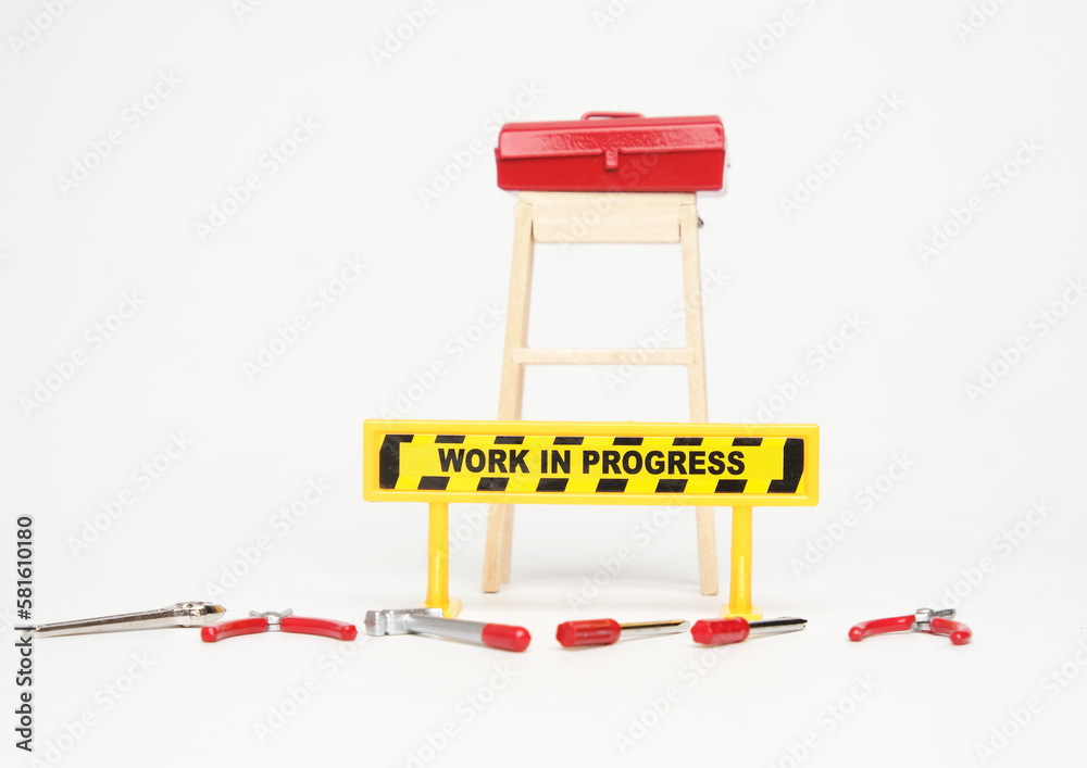 A picture of work in progress sign, tool box, tools and ladder with ...