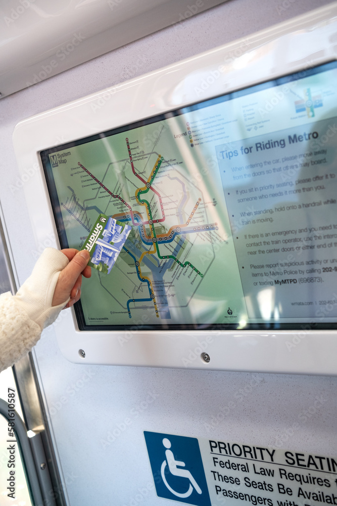 woman holds a SmarTrip subway map and studies the subway map while on a ...