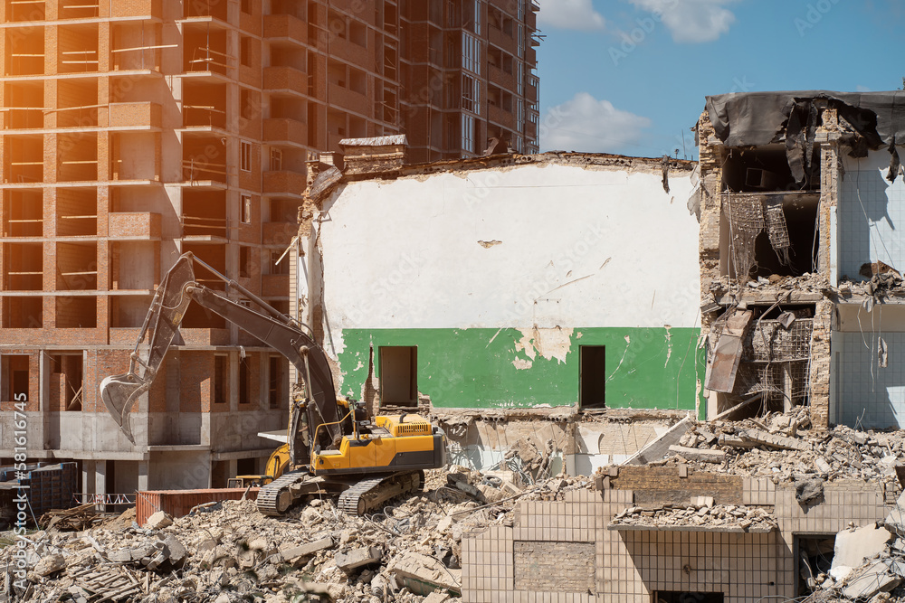 demolition old building by excavator near new construction of modern ...