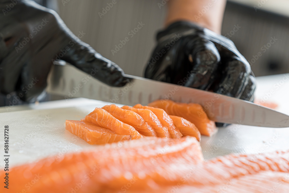Japanese Chef preparing a fresh salmon fillet in kitchen. Close up hand ...