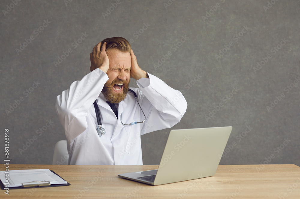Tired crazy male doctor sitting at office table with computer crying ...