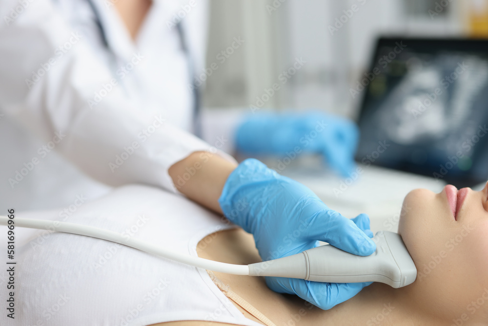 Doctor examining thyroid of female patient with ultrasound scan in ...