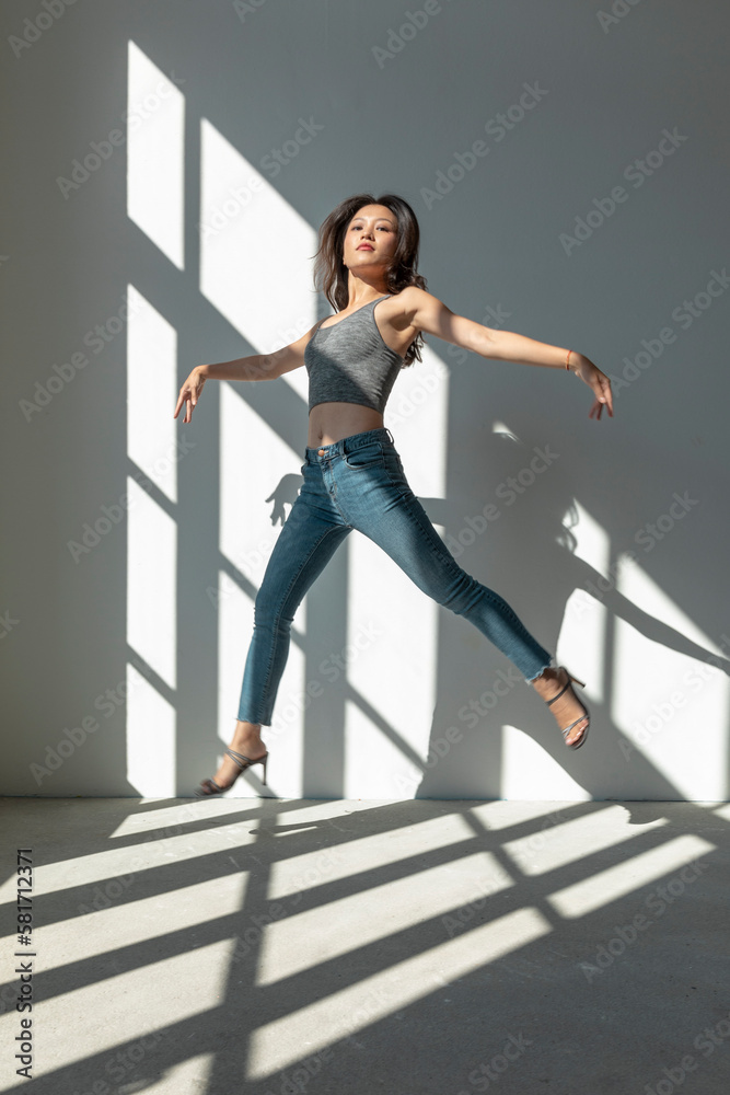 Asian dancer girl makes an acrobatic jump illuminated by the sun that ...