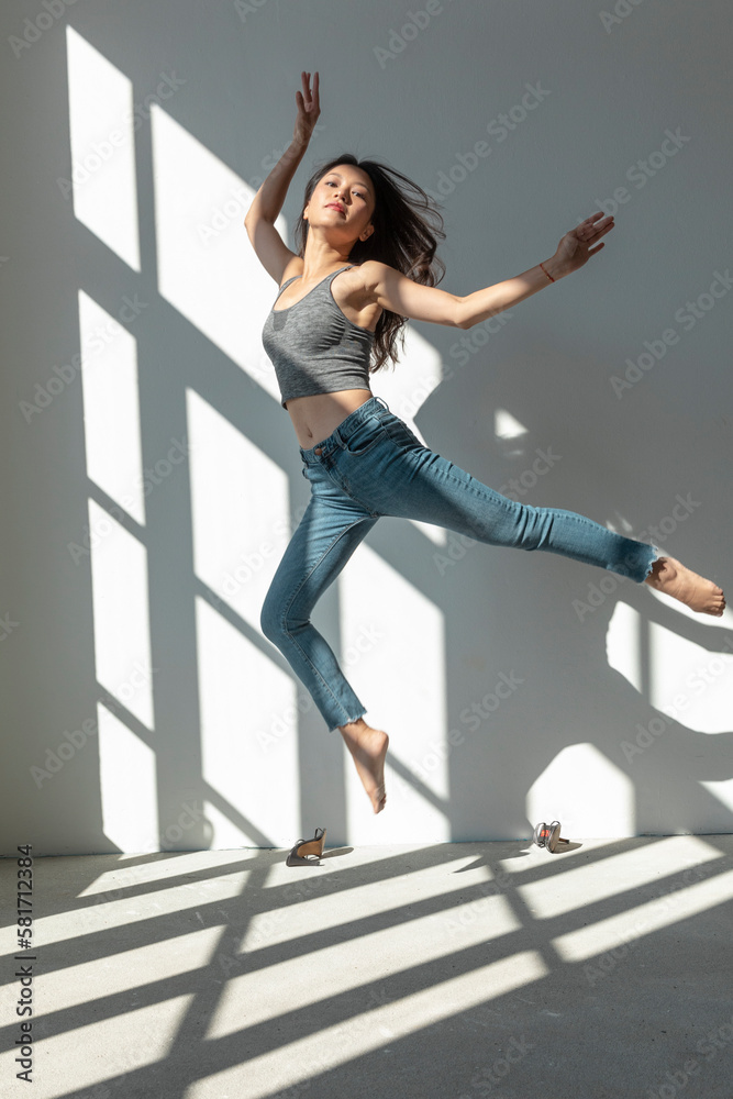 Asian dancer girl makes an acrobatic jump illuminated by the sun that ...