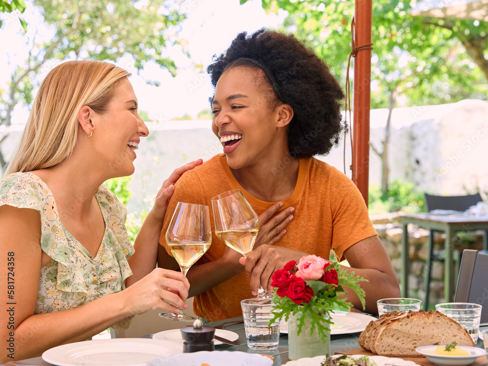 Two Female Friends Enjoying Outdoor Meal And Wine On Visit To Vineyard ...