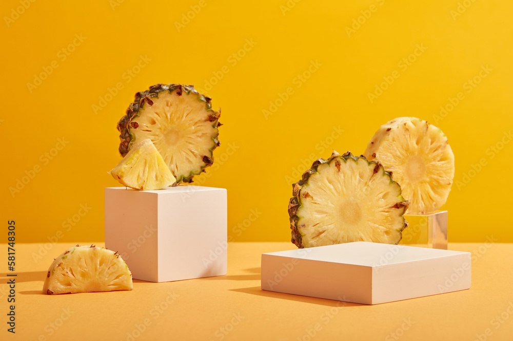 Front view of pineapple fruit cut in half and triangle shape and white empty podium on yellow ...
