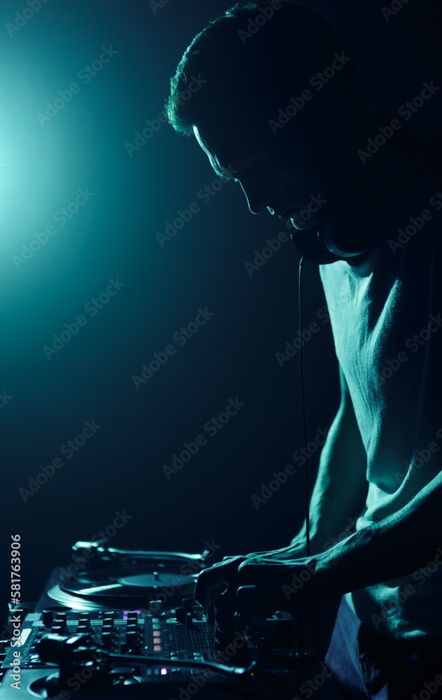 DJ playing techno music in dark nightclub. Silhoutte of cool young disc ...
